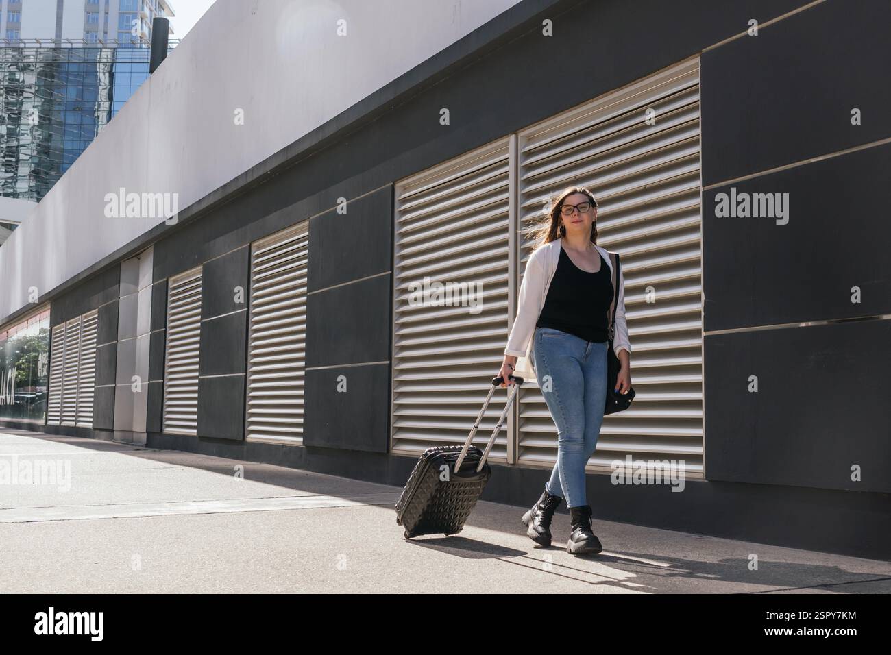 Young business woman walking on the sidewalk next to a modern building ...