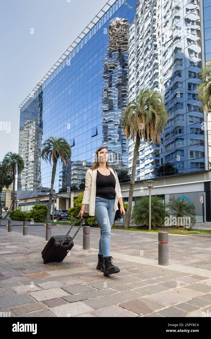 Young business woman pulling her trolley bag while walking on a tiled ...