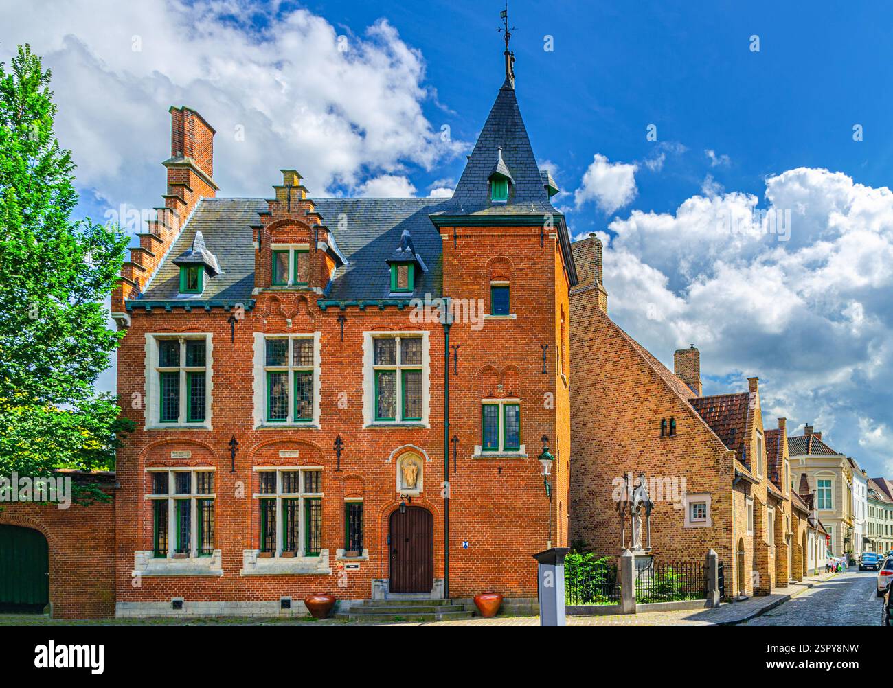 Residential building with tower on cobblestone street in Brugge city ...