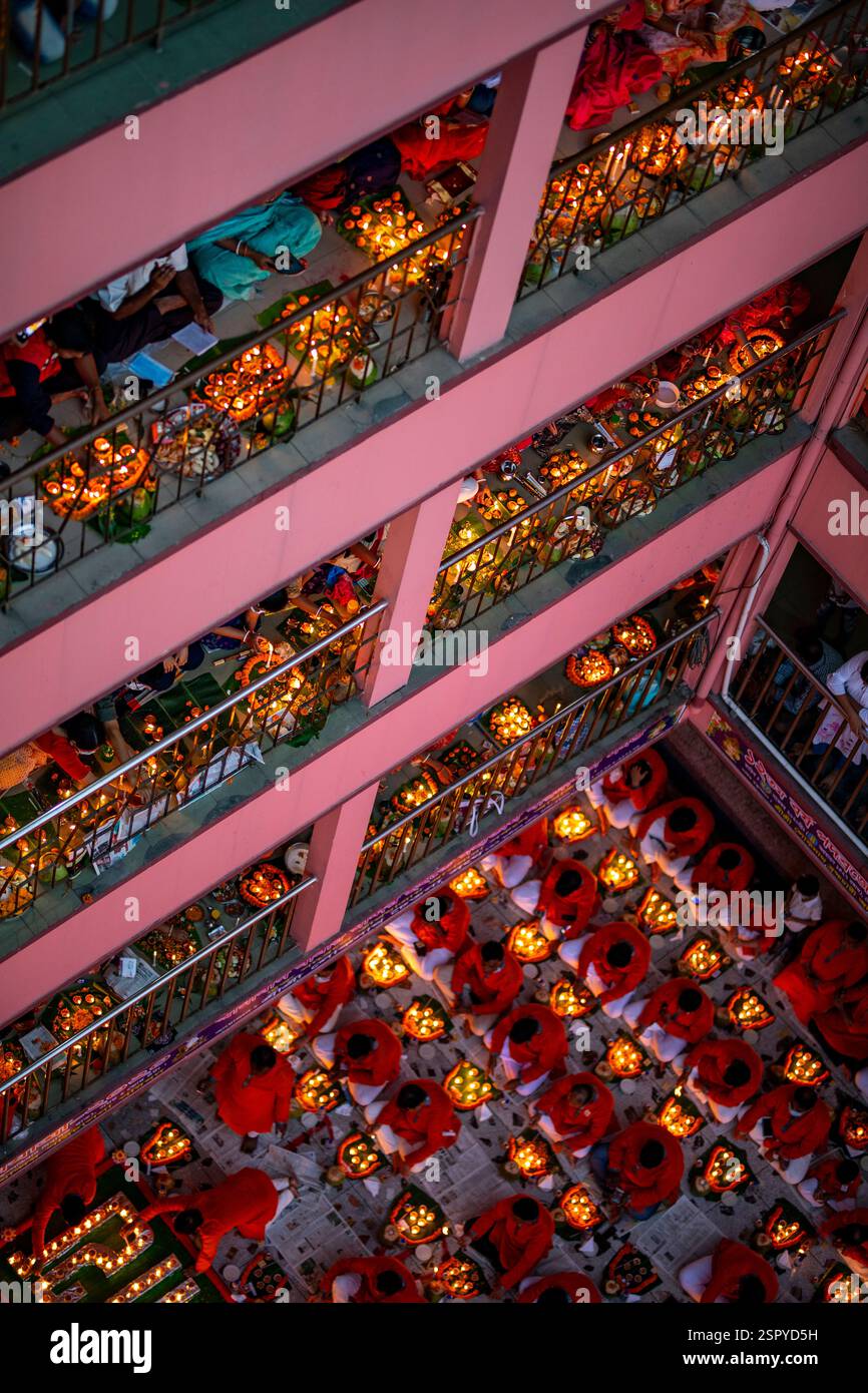 Hindu devotees gather in prayer, lighting oil lamps and burning incense ...
