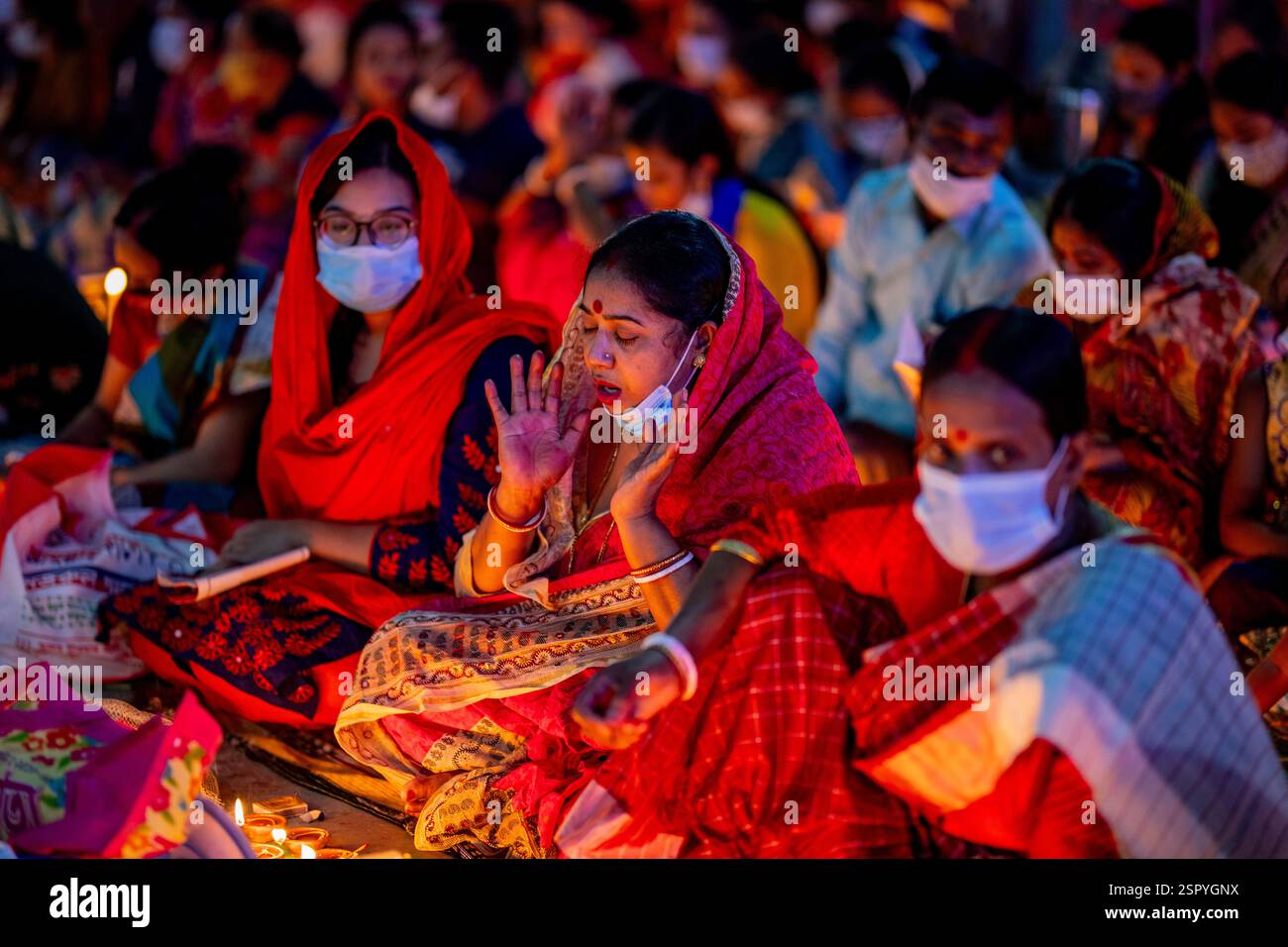 Hindu devotees gather in prayer, lighting oil lamps and burning incense ...