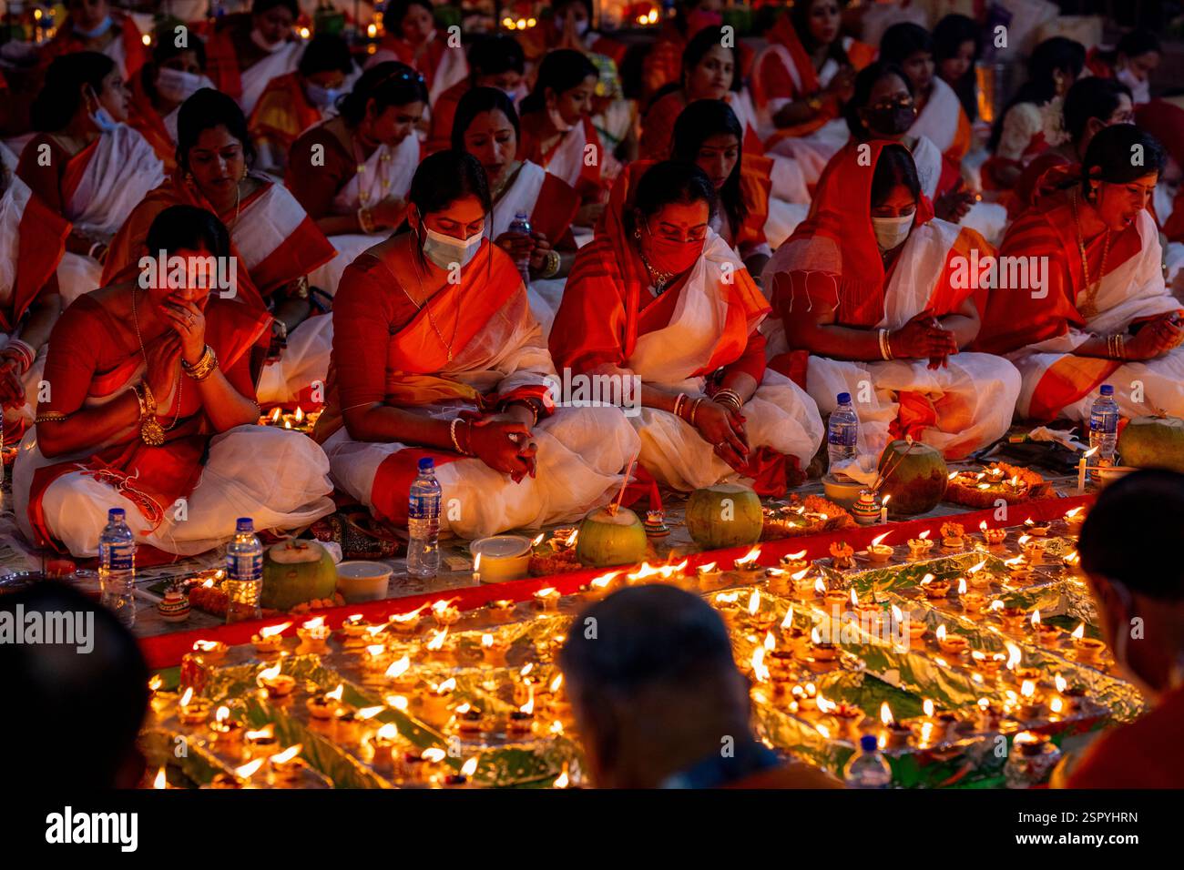 Hindu devotees gather in prayer, lighting oil lamps and burning incense ...
