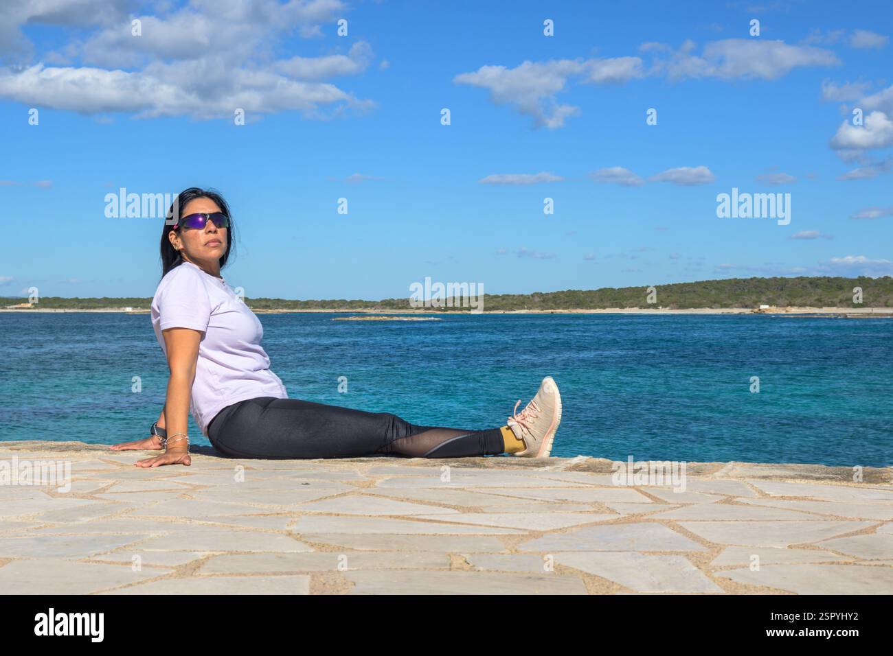latin Woman reclining by the ocean, in a relaxed posture, wearing ...