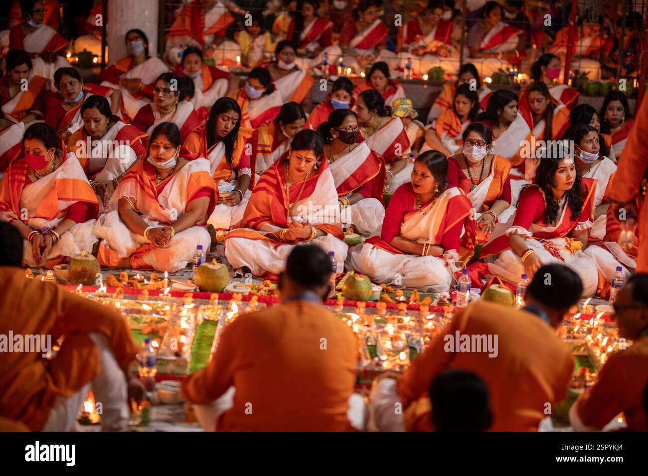 Hindu devotees gather in prayer, lighting oil lamps and burning incense ...