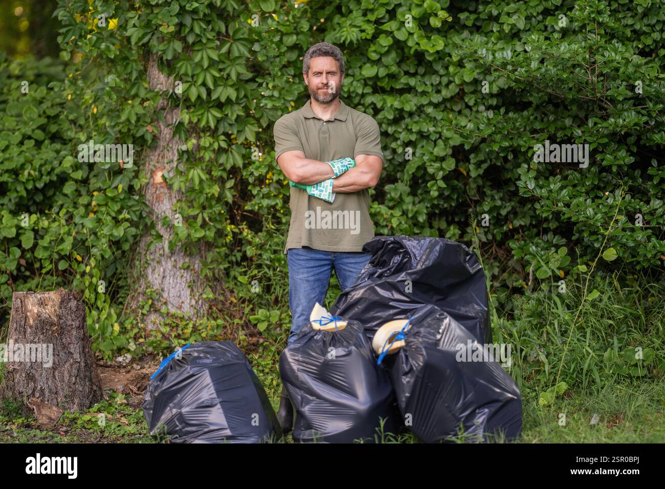 Save environment. Environment plastic pollution. Volunteer man collecting garbage in forest ...
