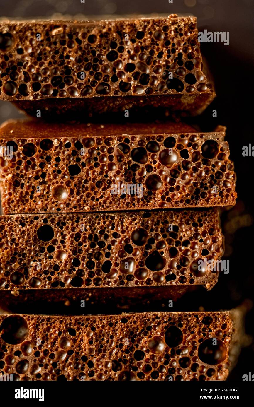 Macro of brown dark porous chocolate. Three stacked pieces against a ...
