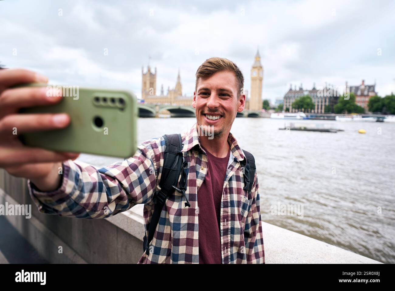 Tourist taking selfie with smartphone in front of big ben and houses of ...