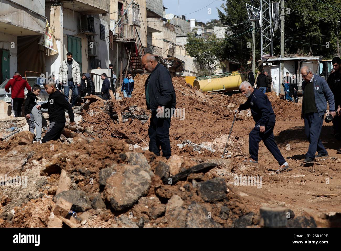 Tubas. 14th Feb, 2025. Palestinian people cross a street destroyed in ...