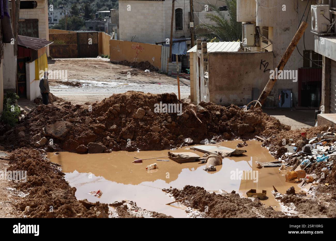 Tubas. 14th Feb, 2025. A Palestinian man stands by a street destroyed ...