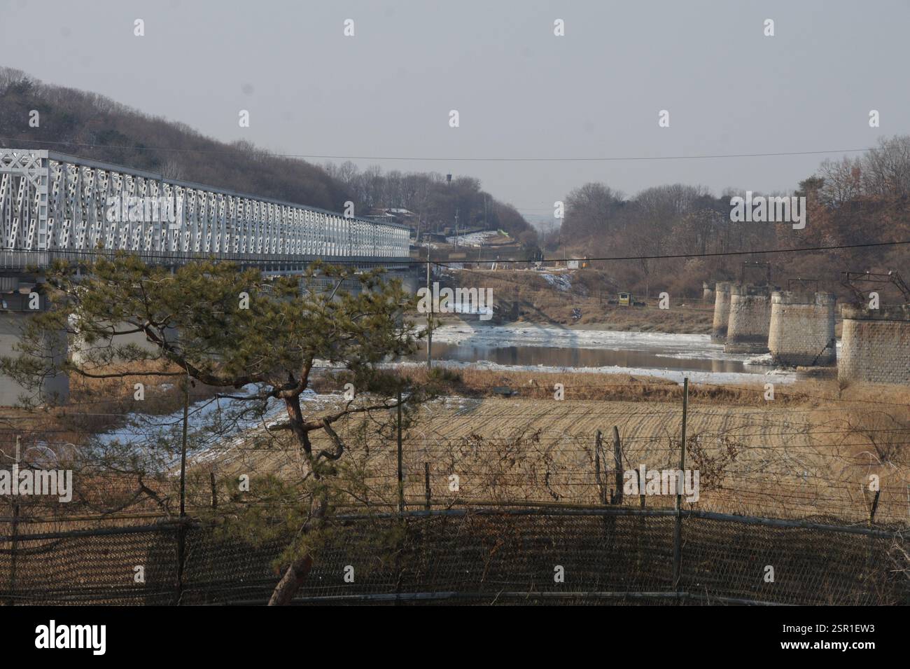 Bridge, long, white structure spanning river, South Korea. Barbed wire ...