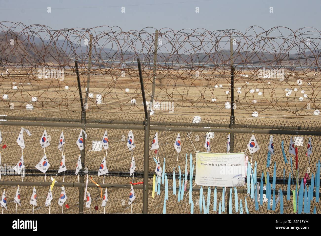 DMZ fence with barbed wire and white bags. Korean flags tied to the ...