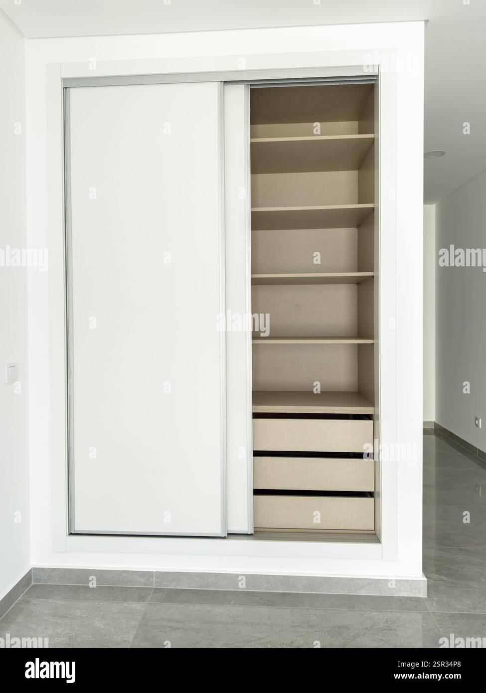 Modern built-in wardrobe with white sliding doors, open to reveal ...