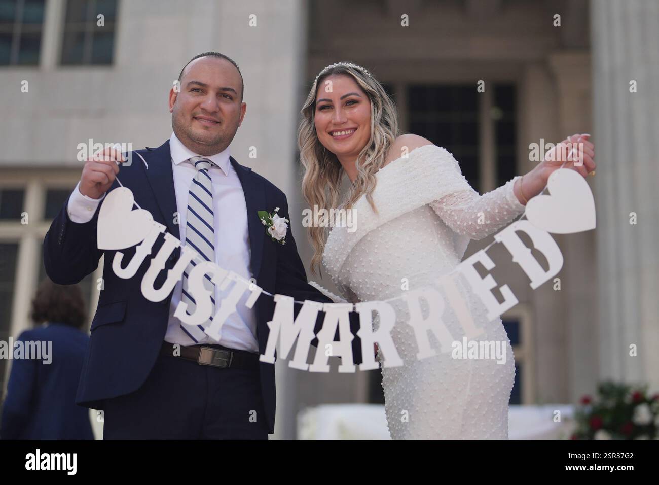 Newlyweds Alianna Mujica, right, and Jose Almao pose with a "Just ...