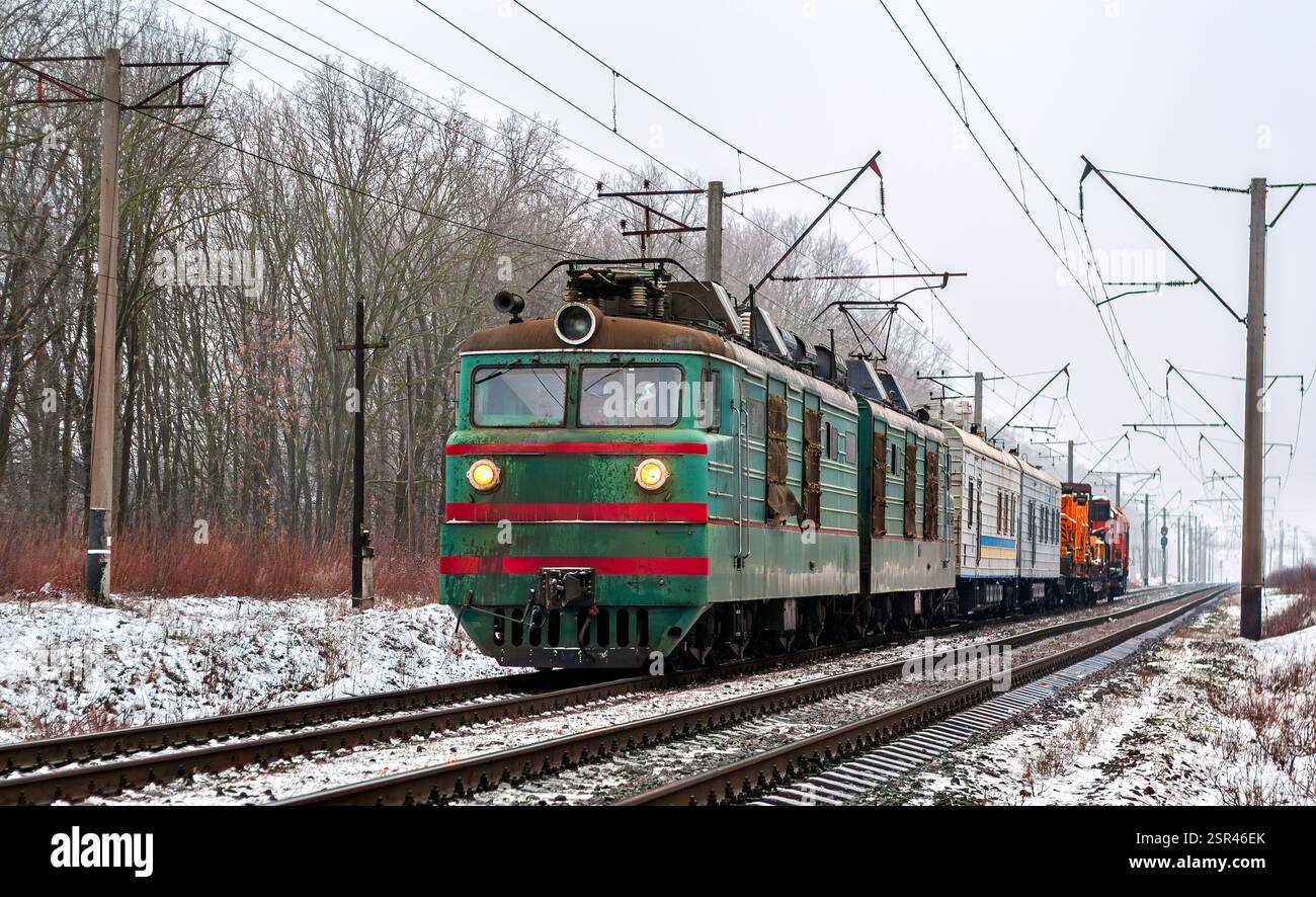 Old Soviet freight electric locomotive with a short train in winter in ...