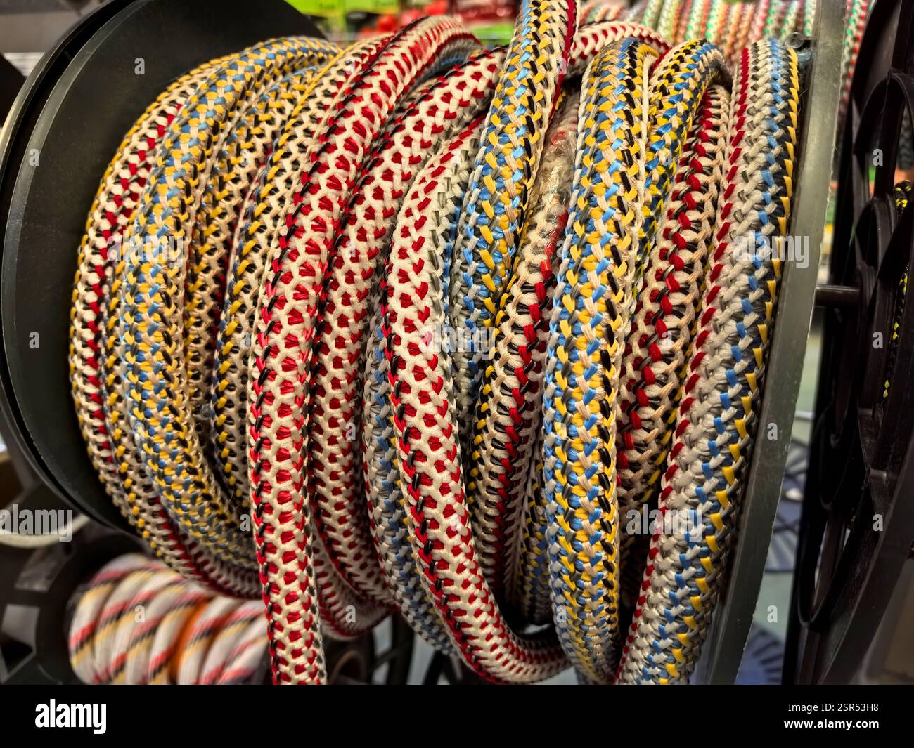 A vibrant assortment of braided ropes is neatly arranged on a spool ...