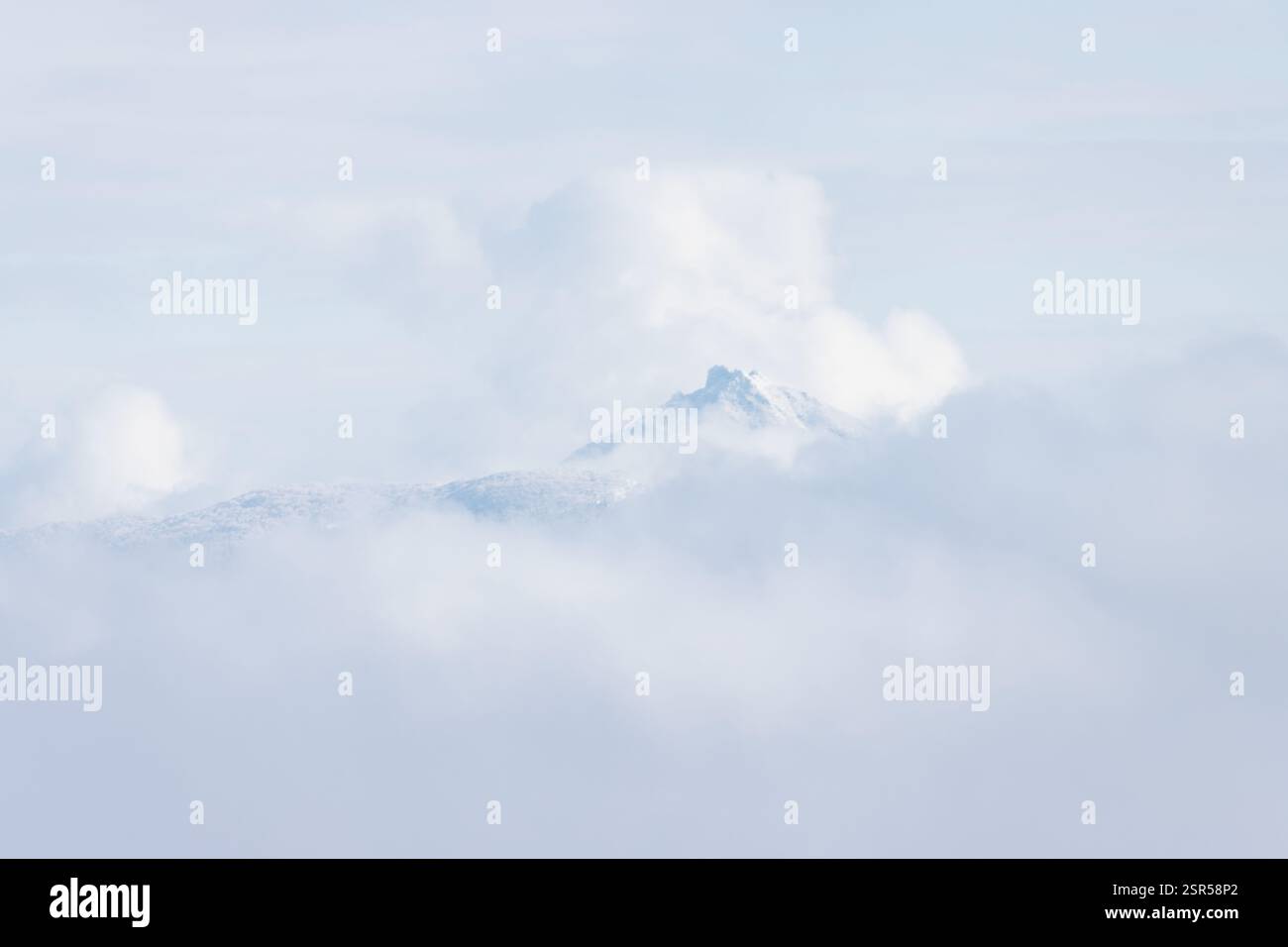 Snow covered winter mountain peak surrounded by soft fluffy white ...