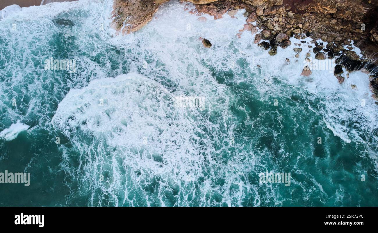Aerial view of ocean waves crashing on rocks in Nazare, Portugal Stock ...