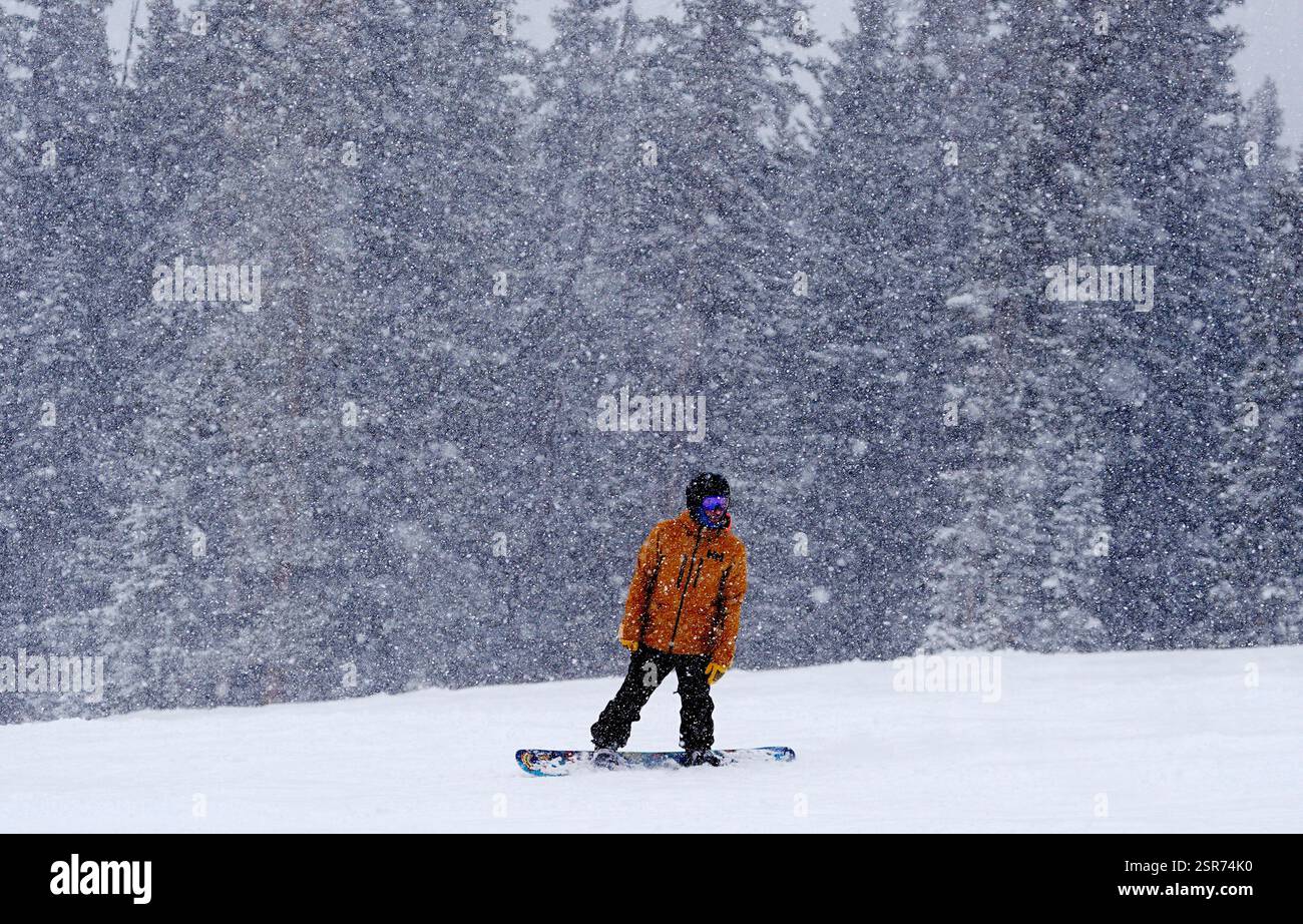 A snowboarder makes his way down a run as a storm sweeps over Loveland ...
