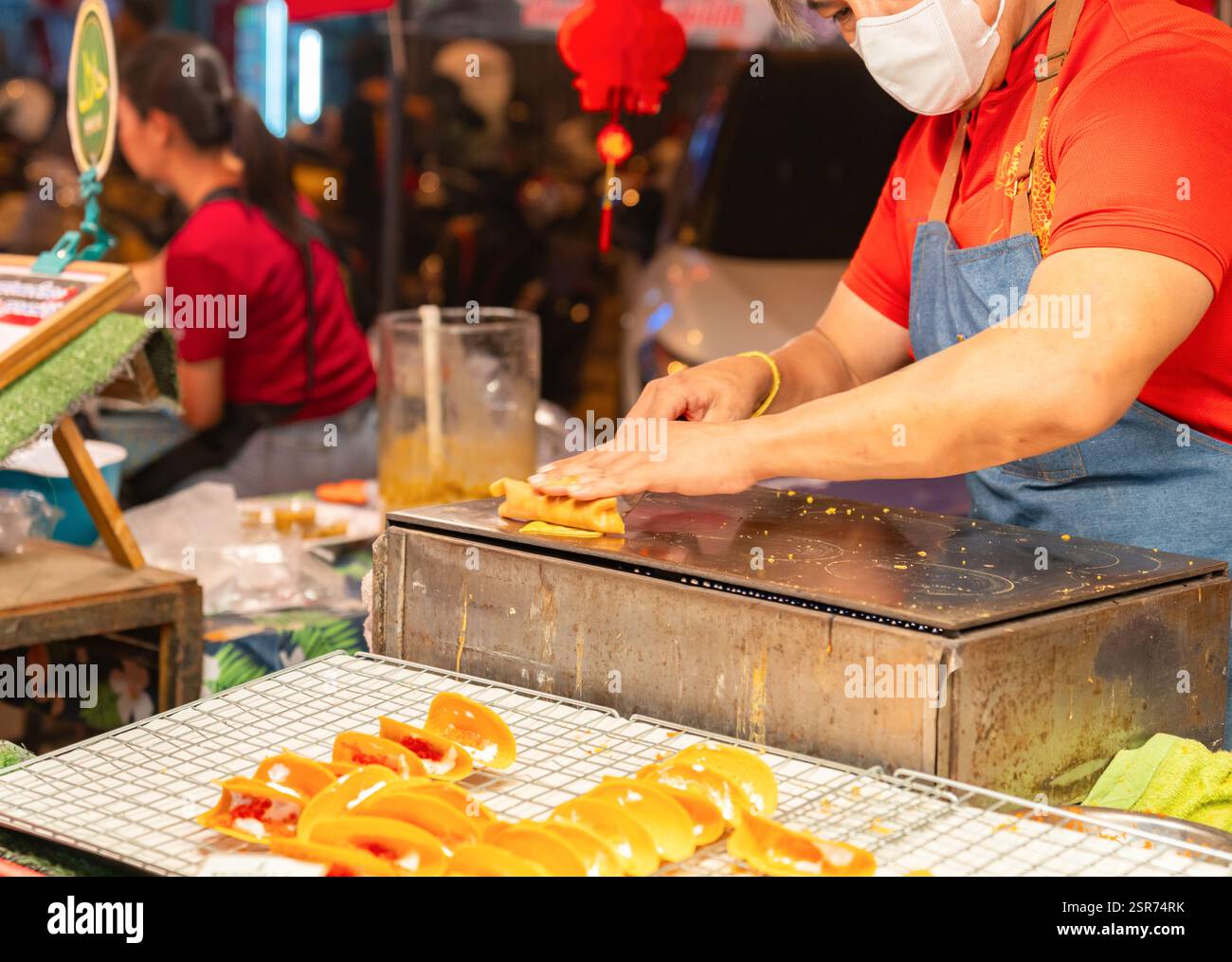 The vendor is folding the crepe on the griddle in chinese street food ...