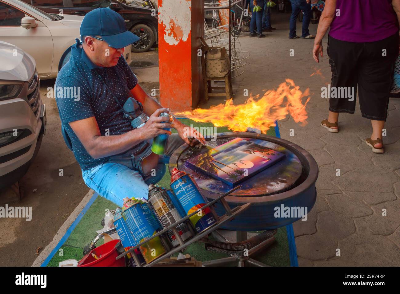 Street artist with aerosol paint canister in his hand, shooting a flame ...