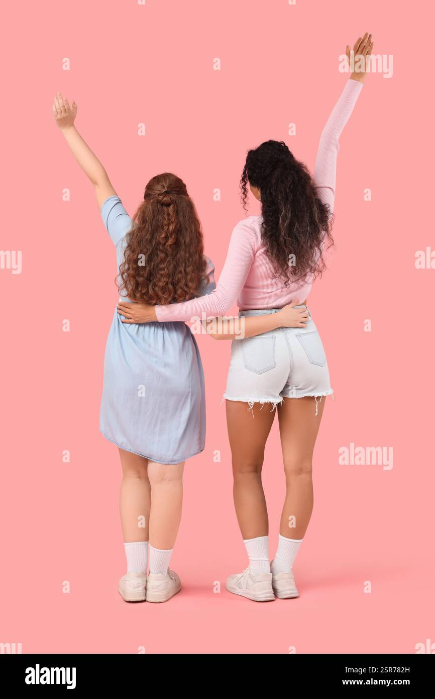 Beautiful young female friends on pink background, back view Stock ...