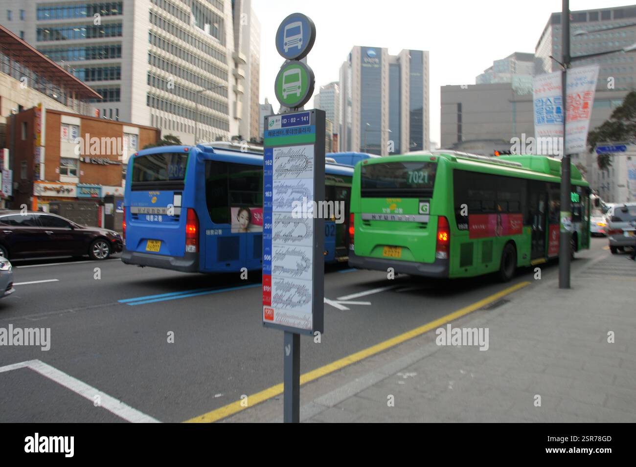 Bus stop in South Korea. Two buses stopped at a bus stop. One blue, one ...