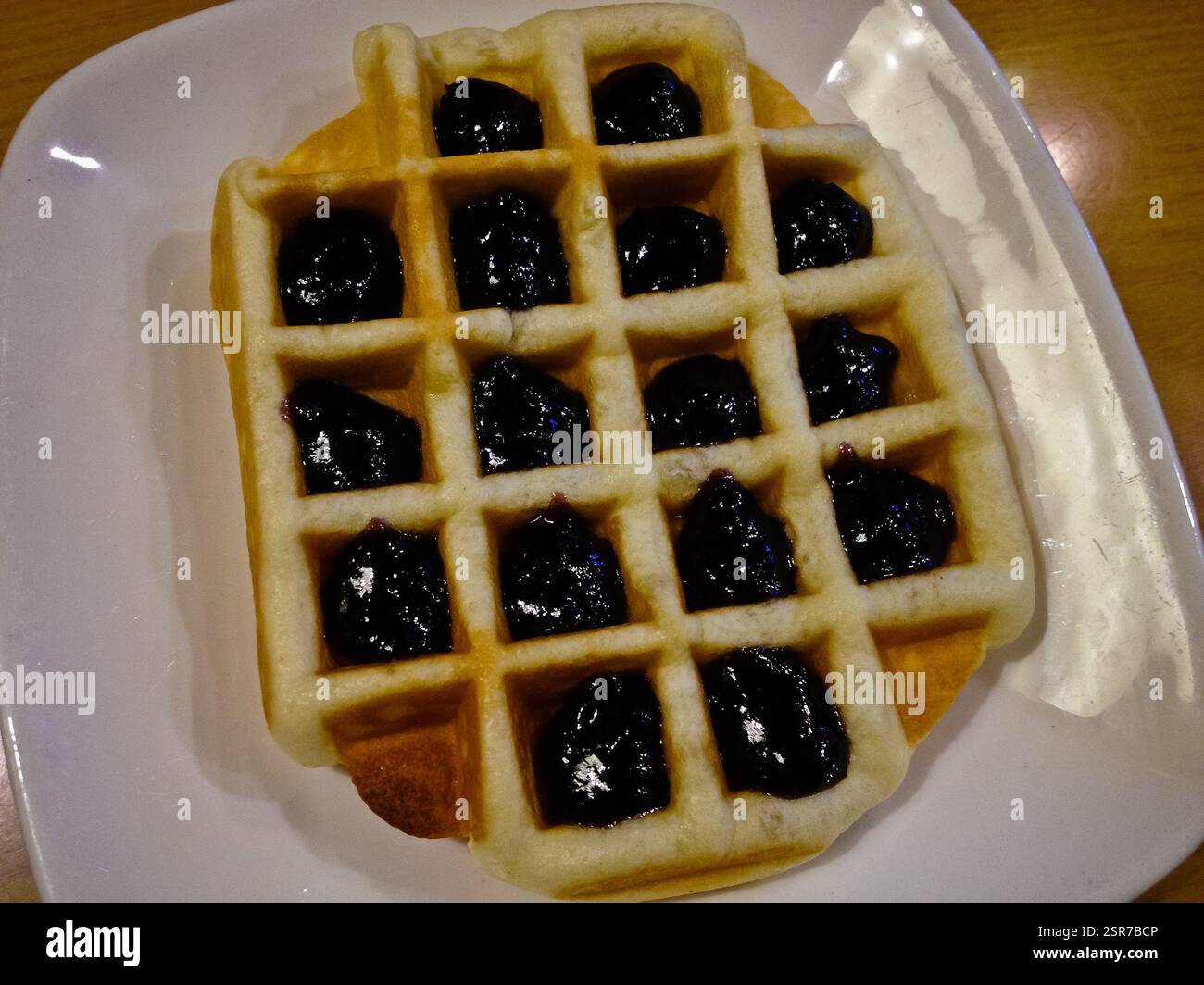 Waffle topped with blueberry jam, a classic breakfast treat. A symbol ...