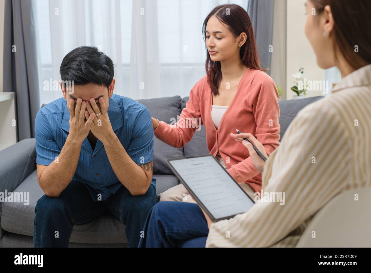distressed asian man covers his face with his hands during a couple's ...