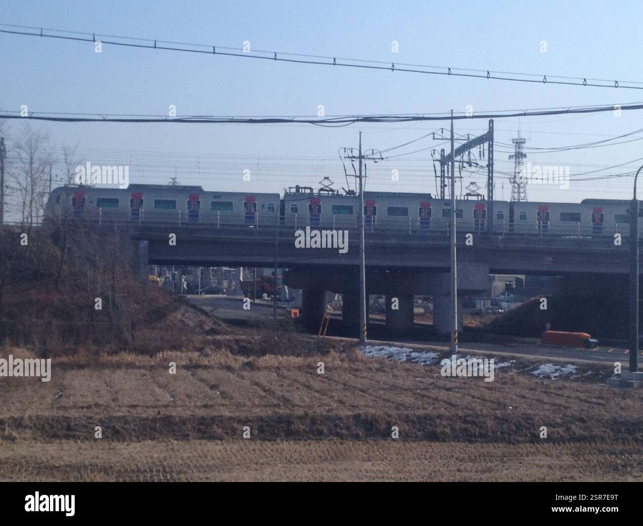 Train on elevated tracks. Several cars with red and white stripes ...
