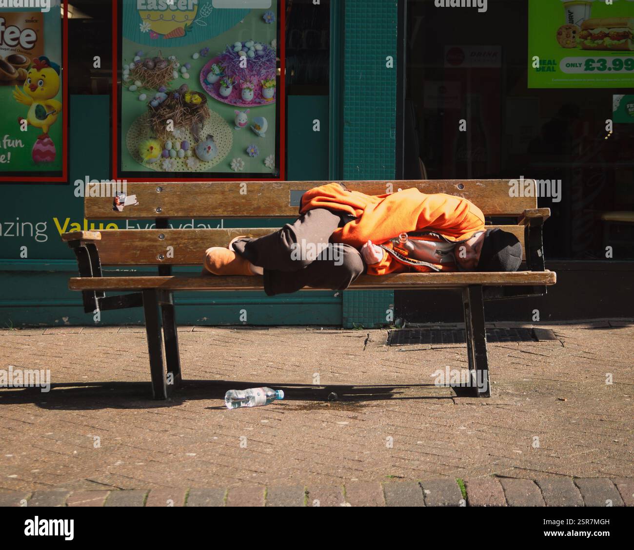 Homeless person asleep on bench in Margate, High street, Kent mid ...