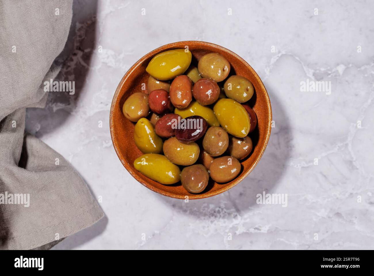 An assortment of various olives presented in a bowl and olive oil ...