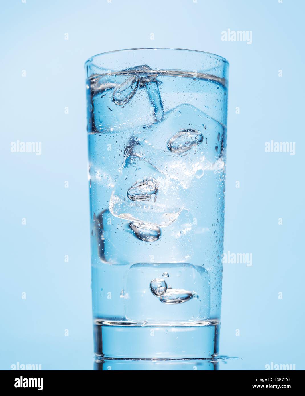 A clear glass filled with chilled water and ice cubes, creating a ...