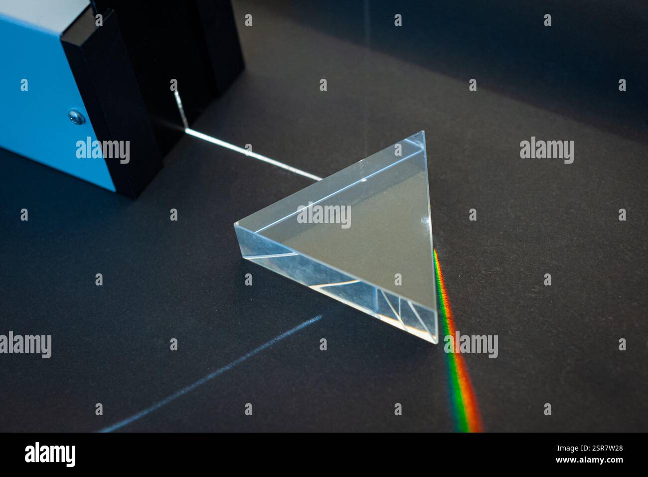 A beam of light is refracted in a triangular piece of glass creating a ...