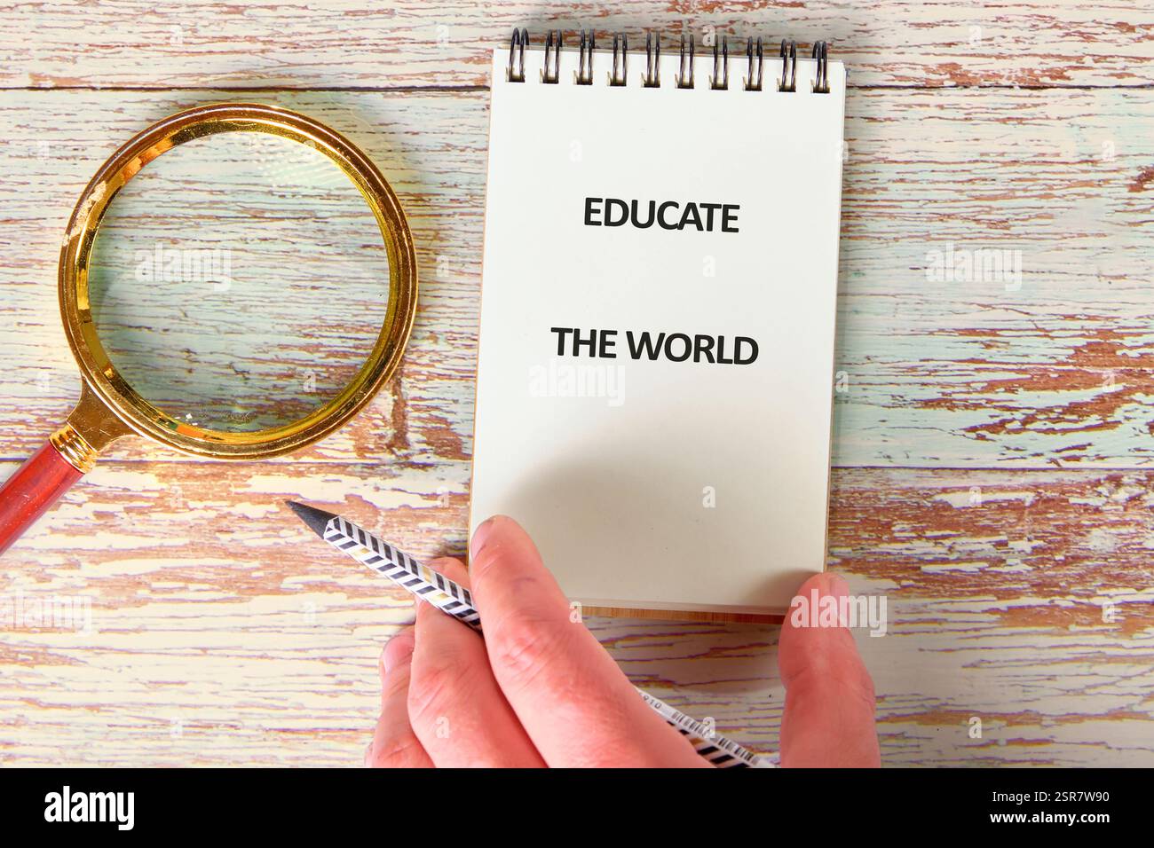 Hand holds a pencil poised over a notepad featuring the phrase educate ...