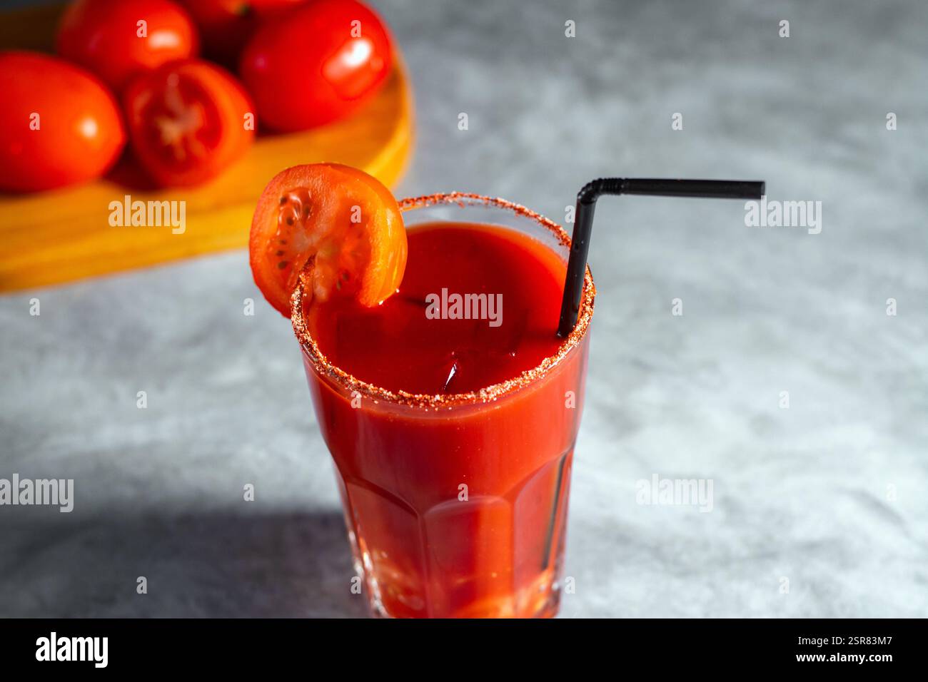 Bloody Mary cocktail in glass served with tomato slice on grey stoned ...