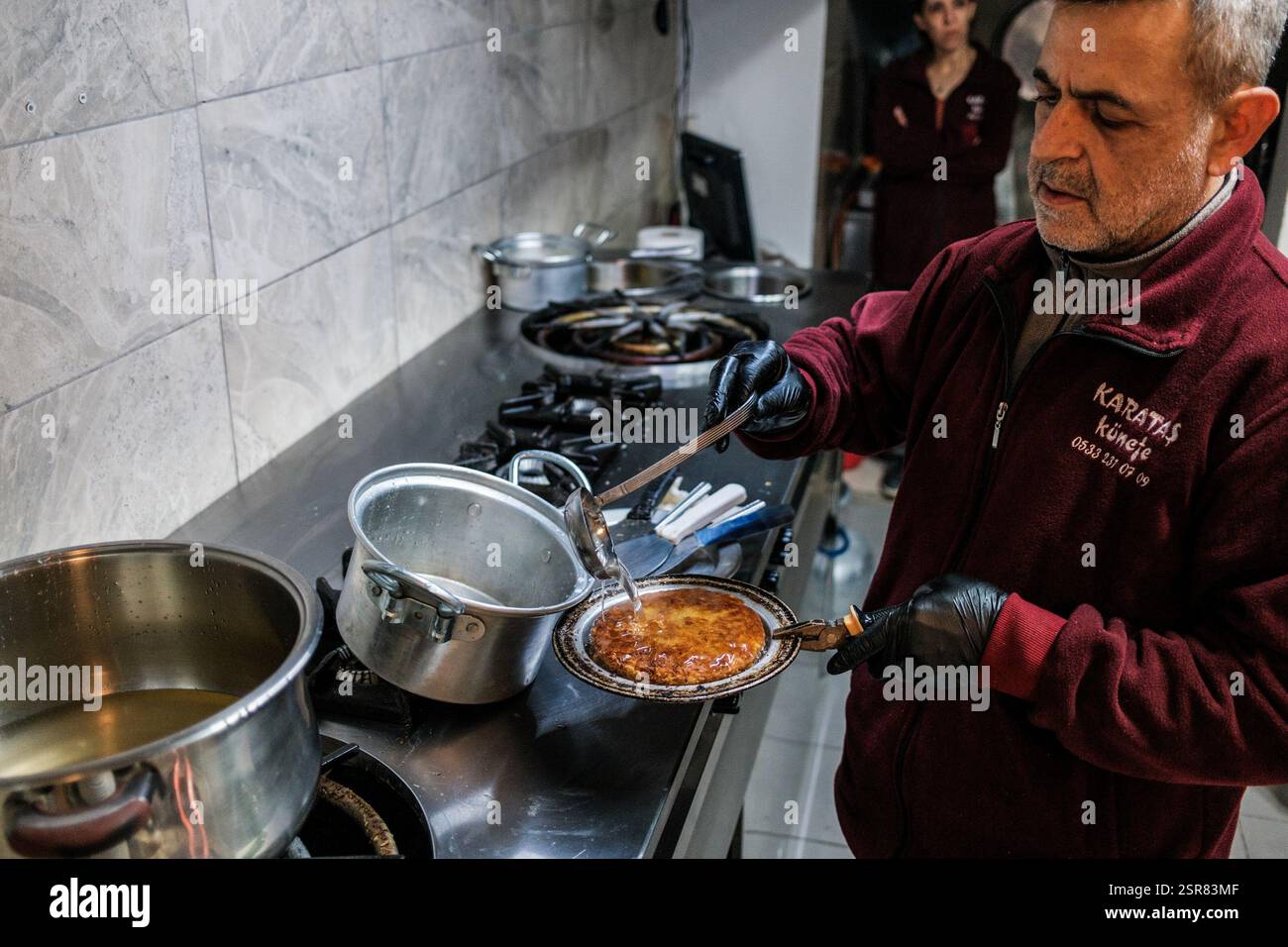 A man pours the syrup for the kunafa. Kunafa, at famous dessert of the ...