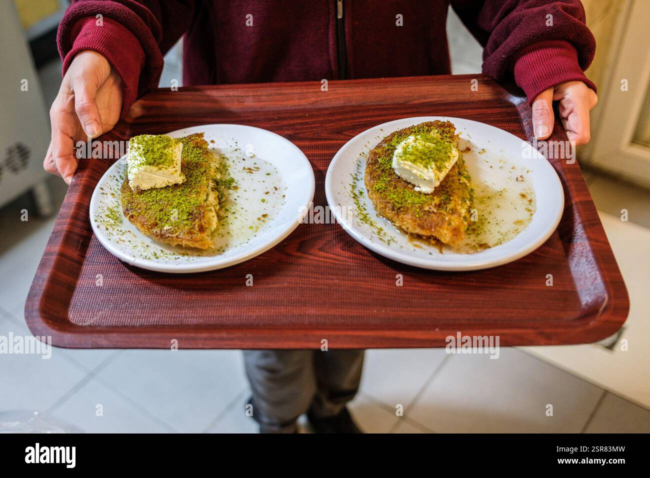 A woman carries kunafa on a tray. Kunafa, at famous dessert of the ...
