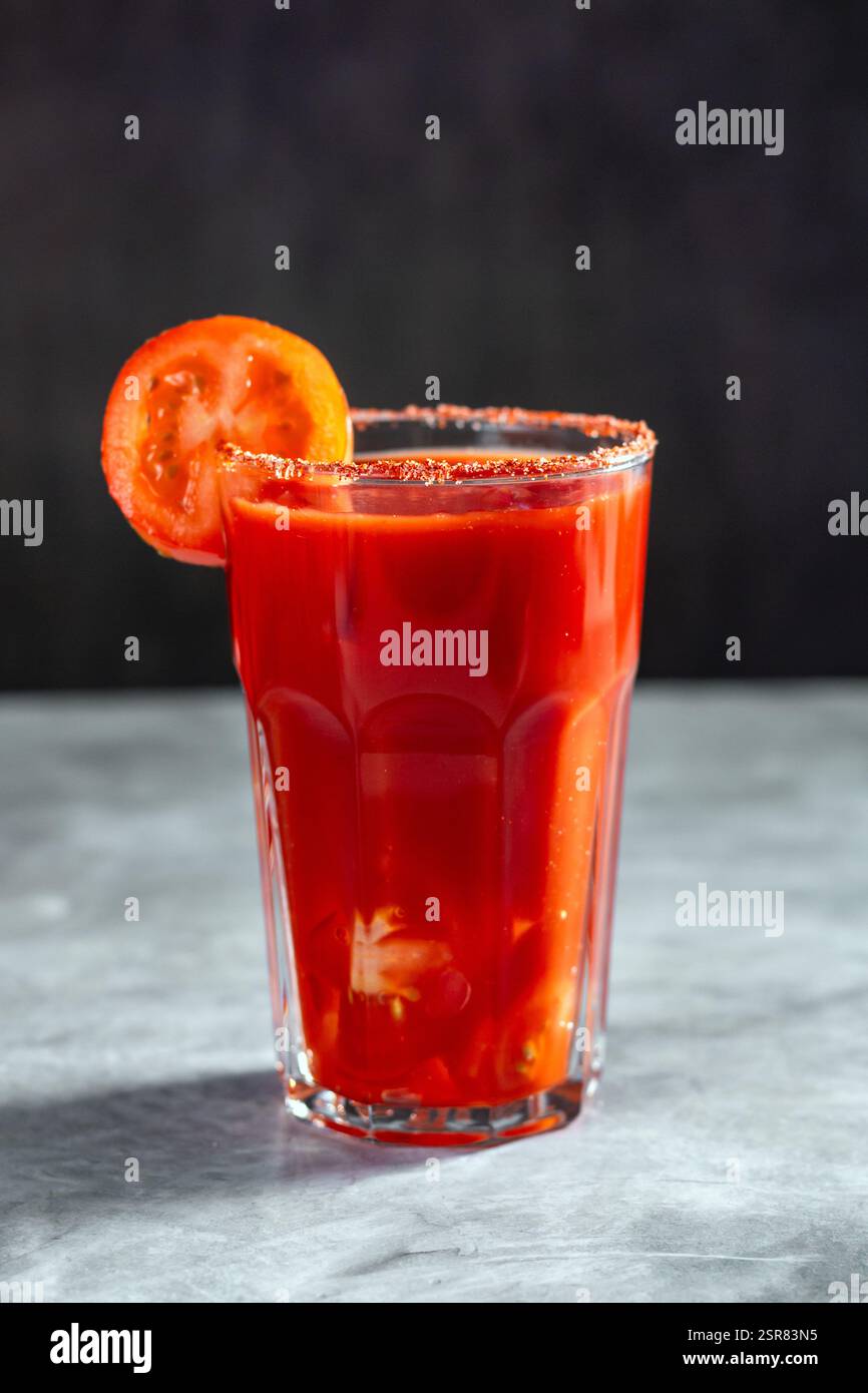 Bloody Mary cocktail in glass served with tomato slice on grey stoned ...