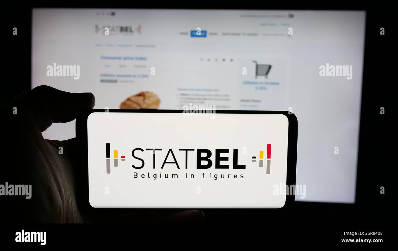 In this photo illustration, a person is holding a cellphone with the logo of agency Statistics ...