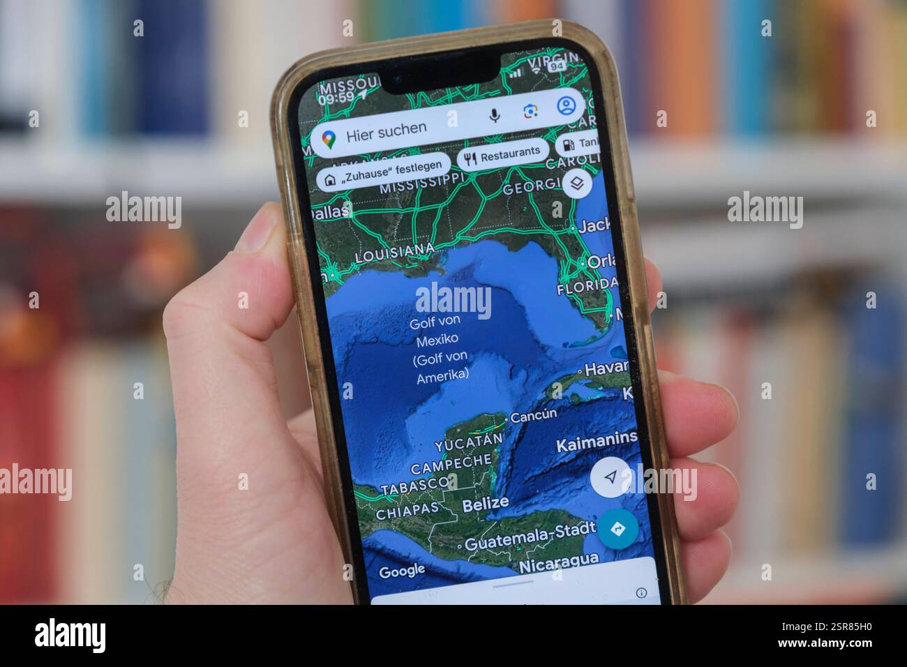 Hand mit Mobiltelefon auf der ein Kartenausschnitt mit dem Golf von ...