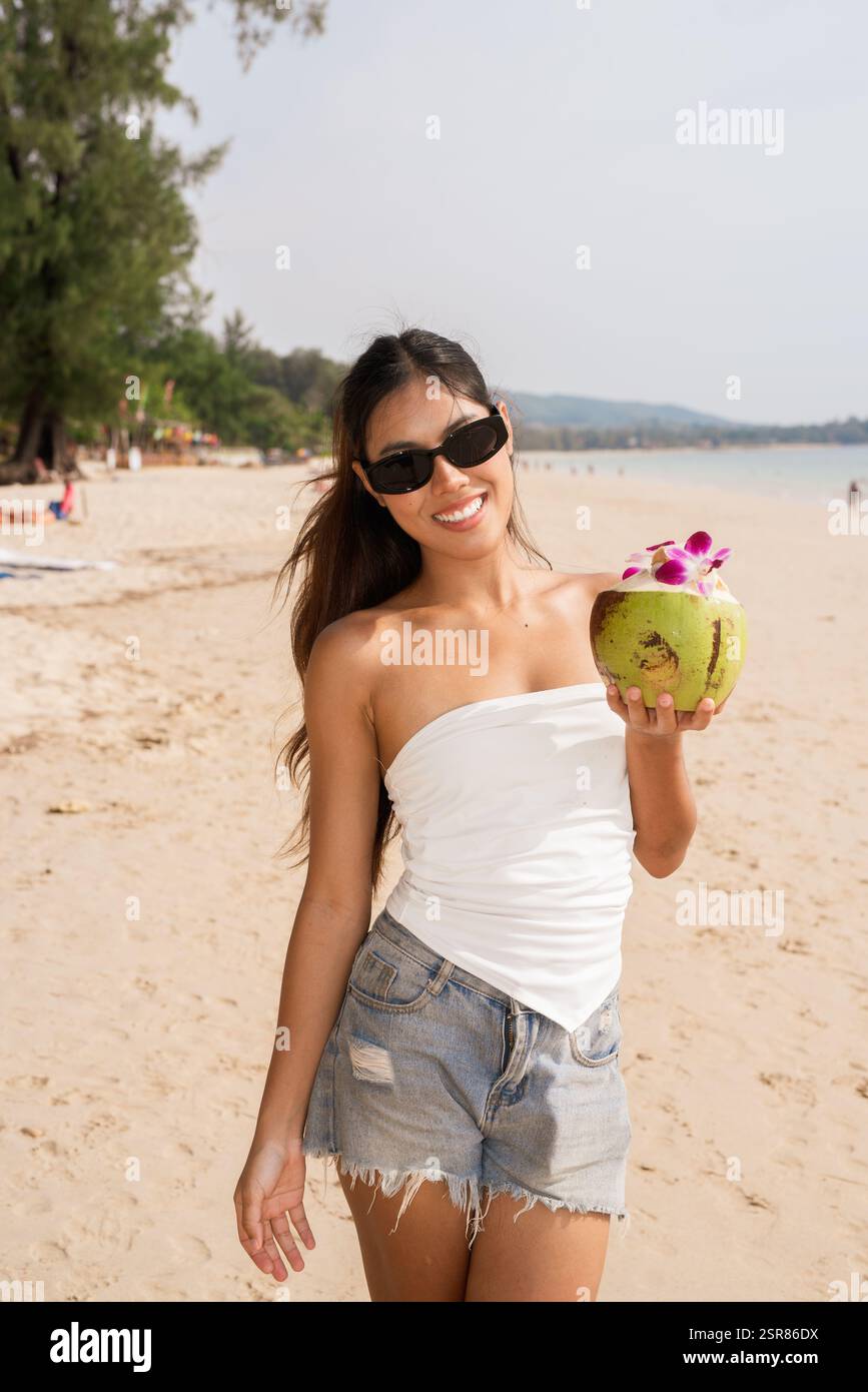 Young beautiful Asian woman smiling with coconut on beach Stock Photo ...