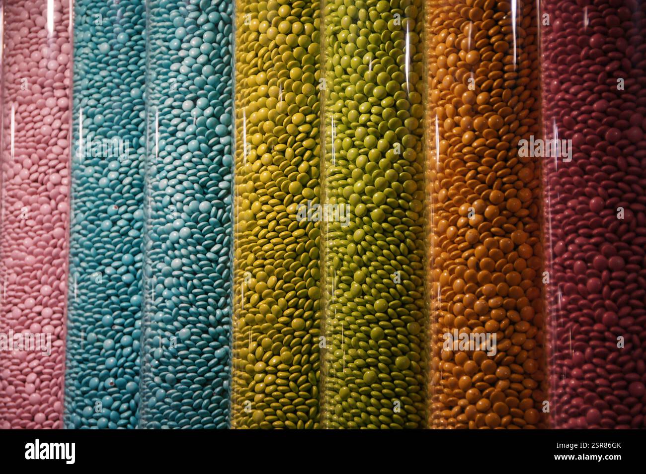 Brightly colored candy fills tall tubes in a dispenser, creating a ...
