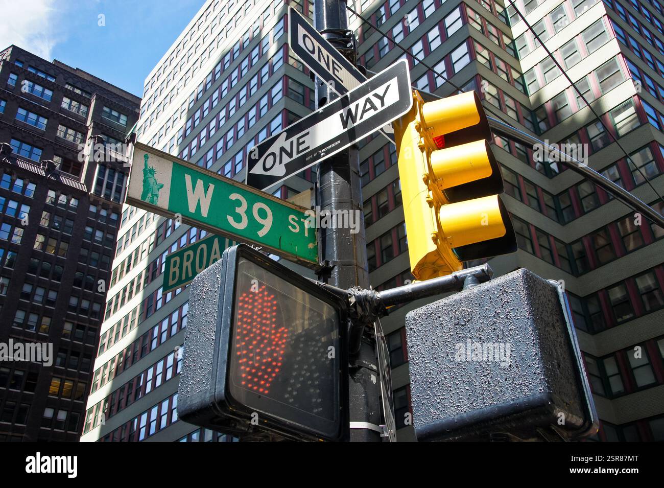 A traffic light and street signs hang on a pole in bustling New York ...