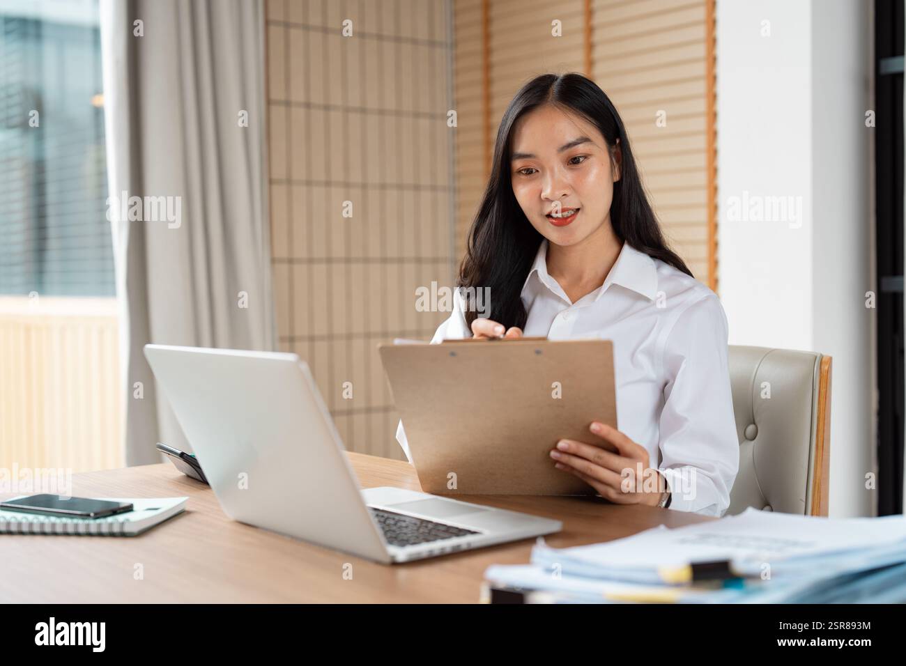 Engaged businesswoman reviewing her notes, focused at her desk in a ...