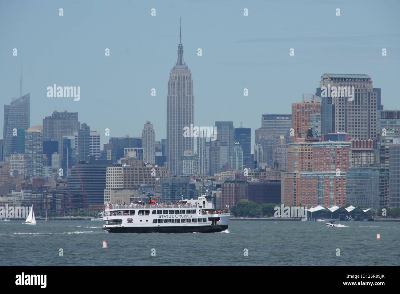 A ferry tour in New York City. The ferry cuts through the water, the iconic Manhattan skyline ...