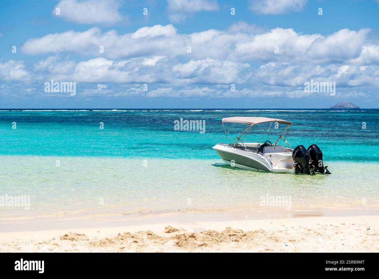 Touristic speed boat waiting by the shore in front of the tropical horizon of Mauritius Island ...