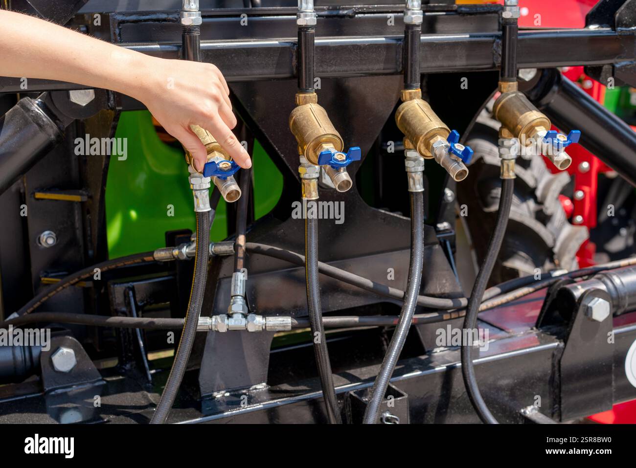 Farmer adjusting flow control valve on agricultural machinery. Valves ...