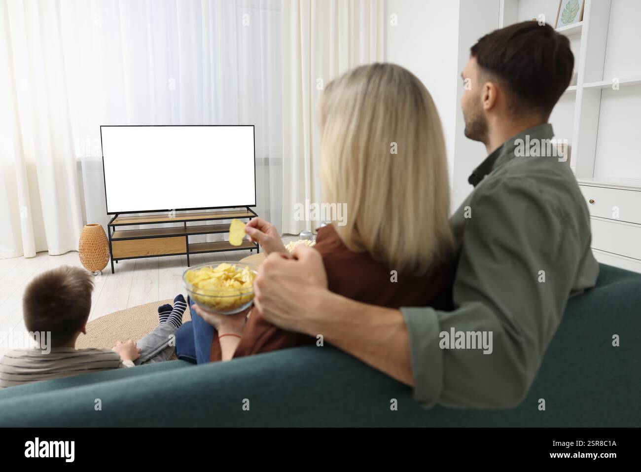 Happy family with snacks and drinks watching tv together at home Stock ...