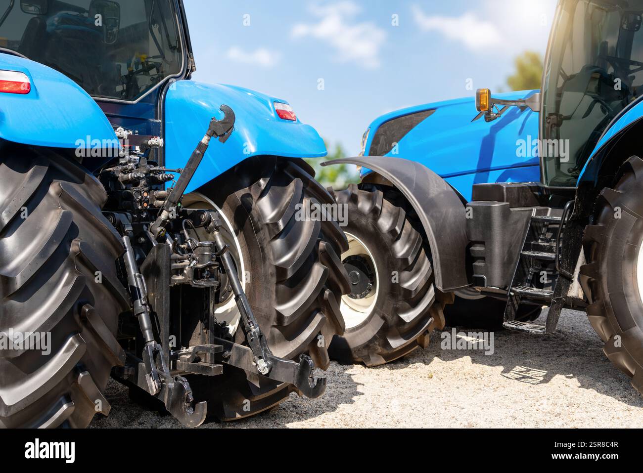 Rear view of blue tractors on display outdoors at a farmland dealership ...