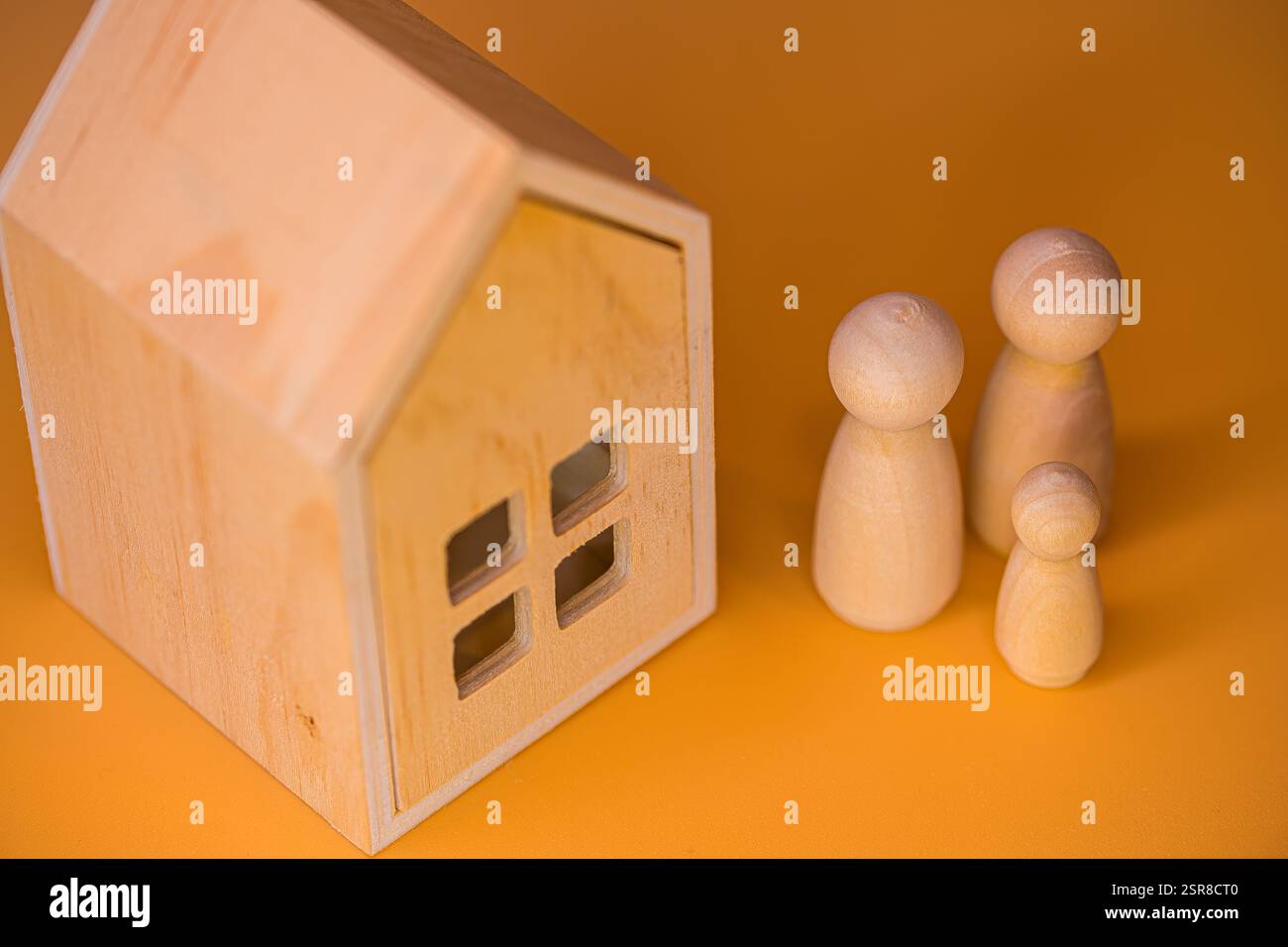 Wooden figurines resembling a family beside a small wooden house model ...